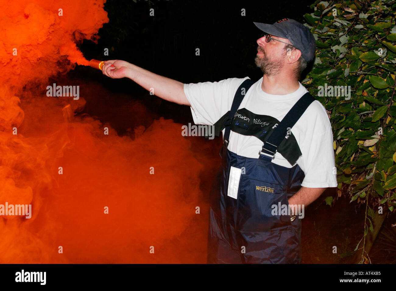 Man in sailing gear lights a Orange daylight distress flare Stock Photo ...