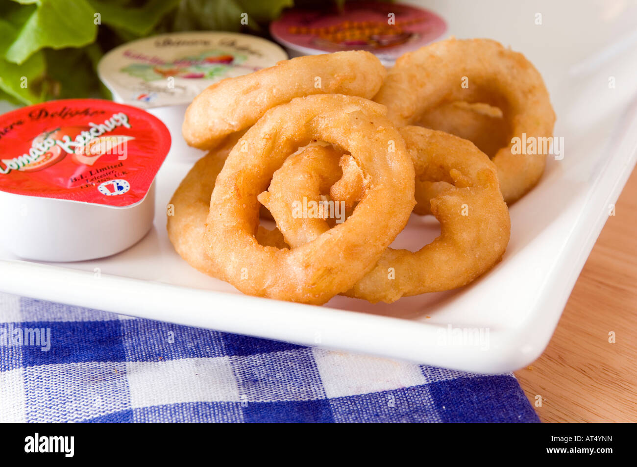 A plate of golden onion rings displayed with a range of packaged dips ...