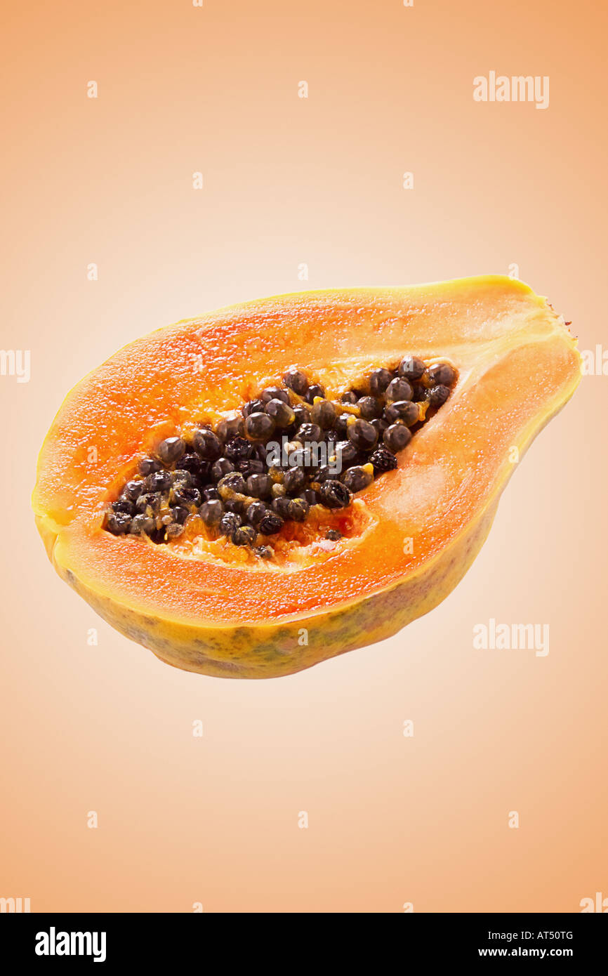 a single halved papaya on pale matching peach coloured background Stock ...