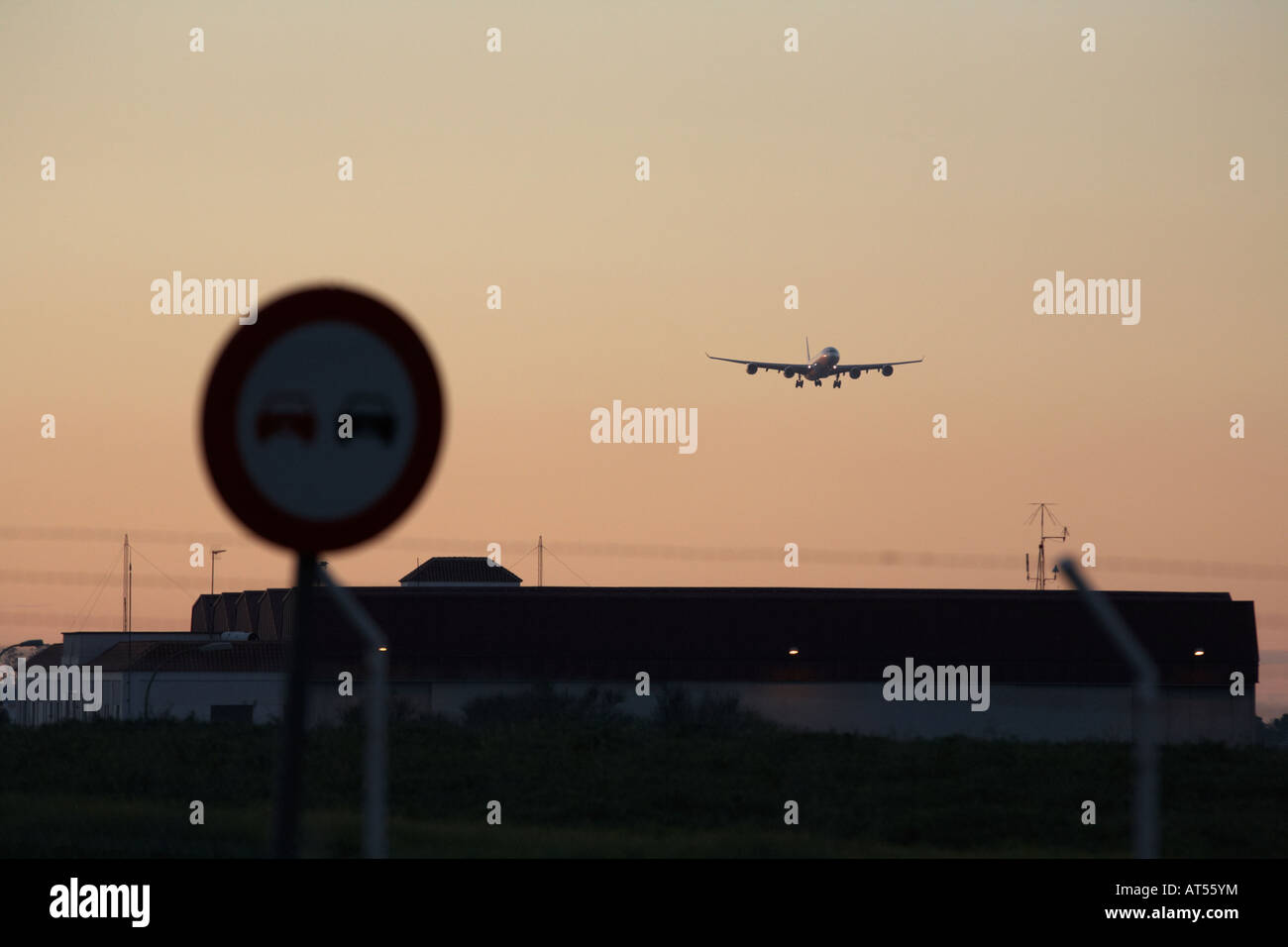 aircraft on final approach in evening light over perimeter fence ...