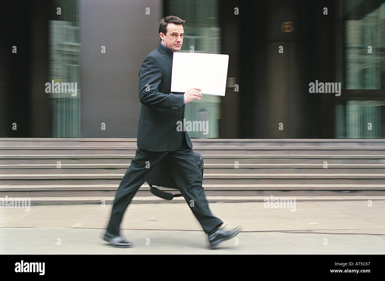 man walking in city street holding sign or document Stock Photo - Alamy