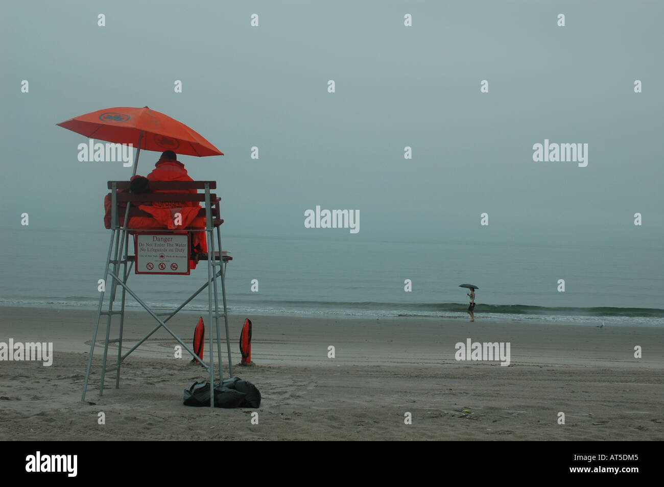 Lifeguard sitting on lifeguard chair during a drizzle rainy day in ...