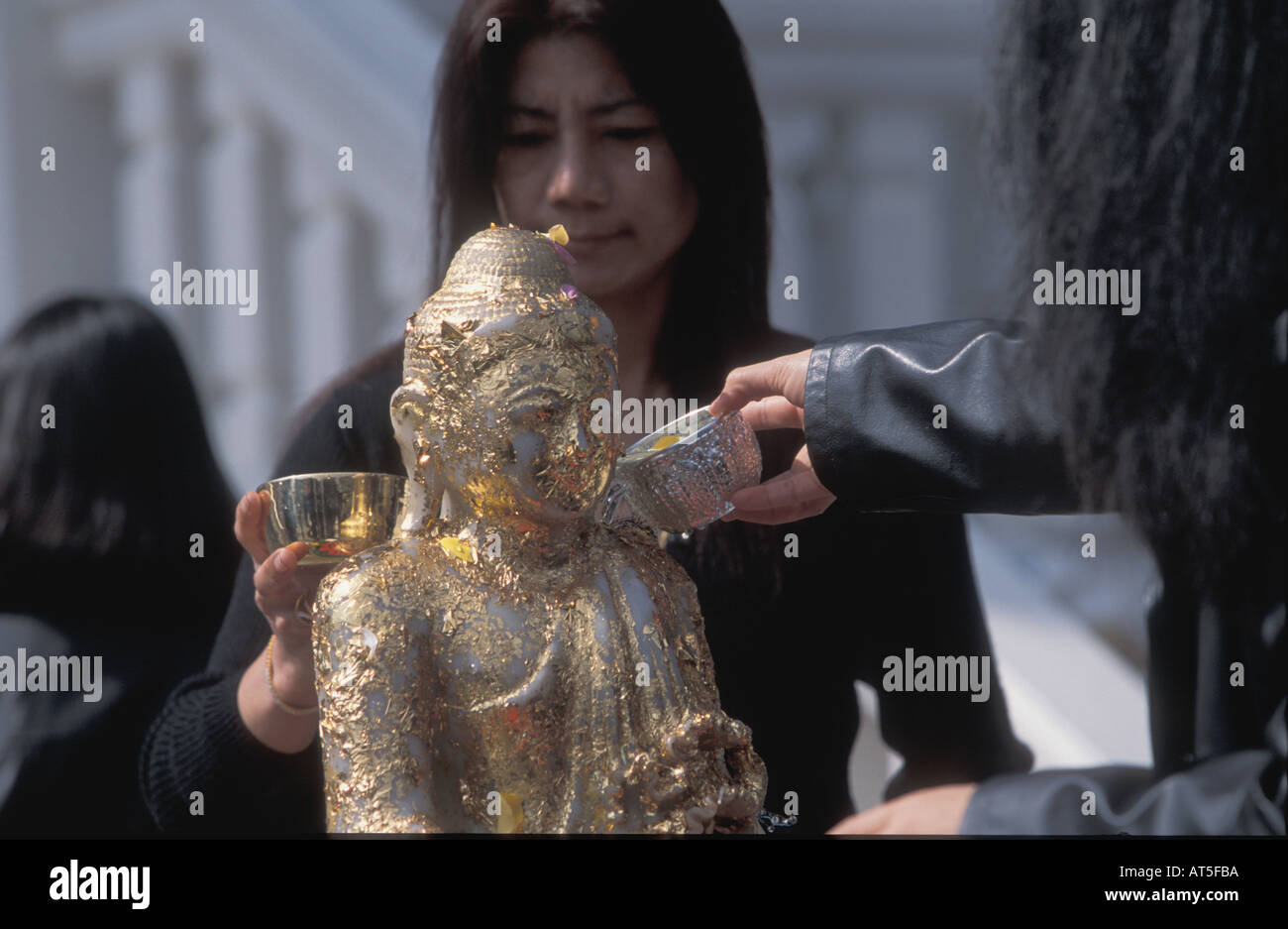 A Buddhist woman bathing a statue of the Buddha on the occasion of ...