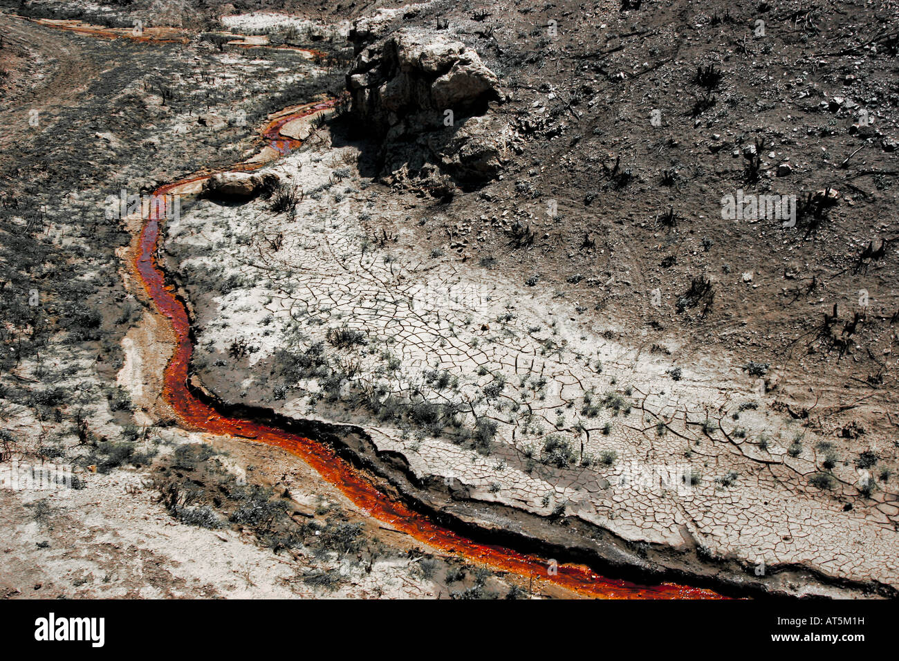 A small red river crossing a dry land Stock Photo - Alamy