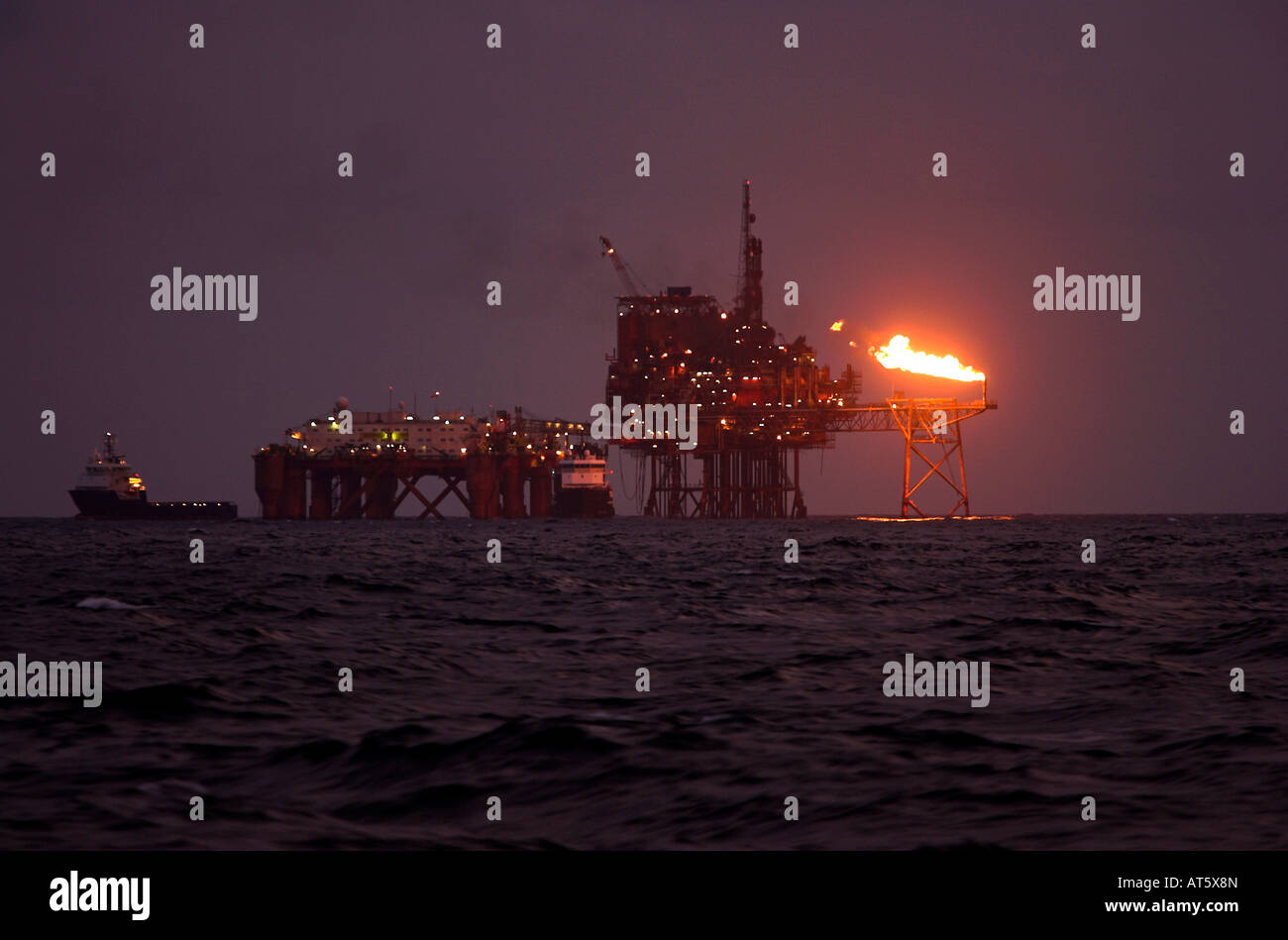 massive rig complex with 2 supply boats at night in north sea Stock ...