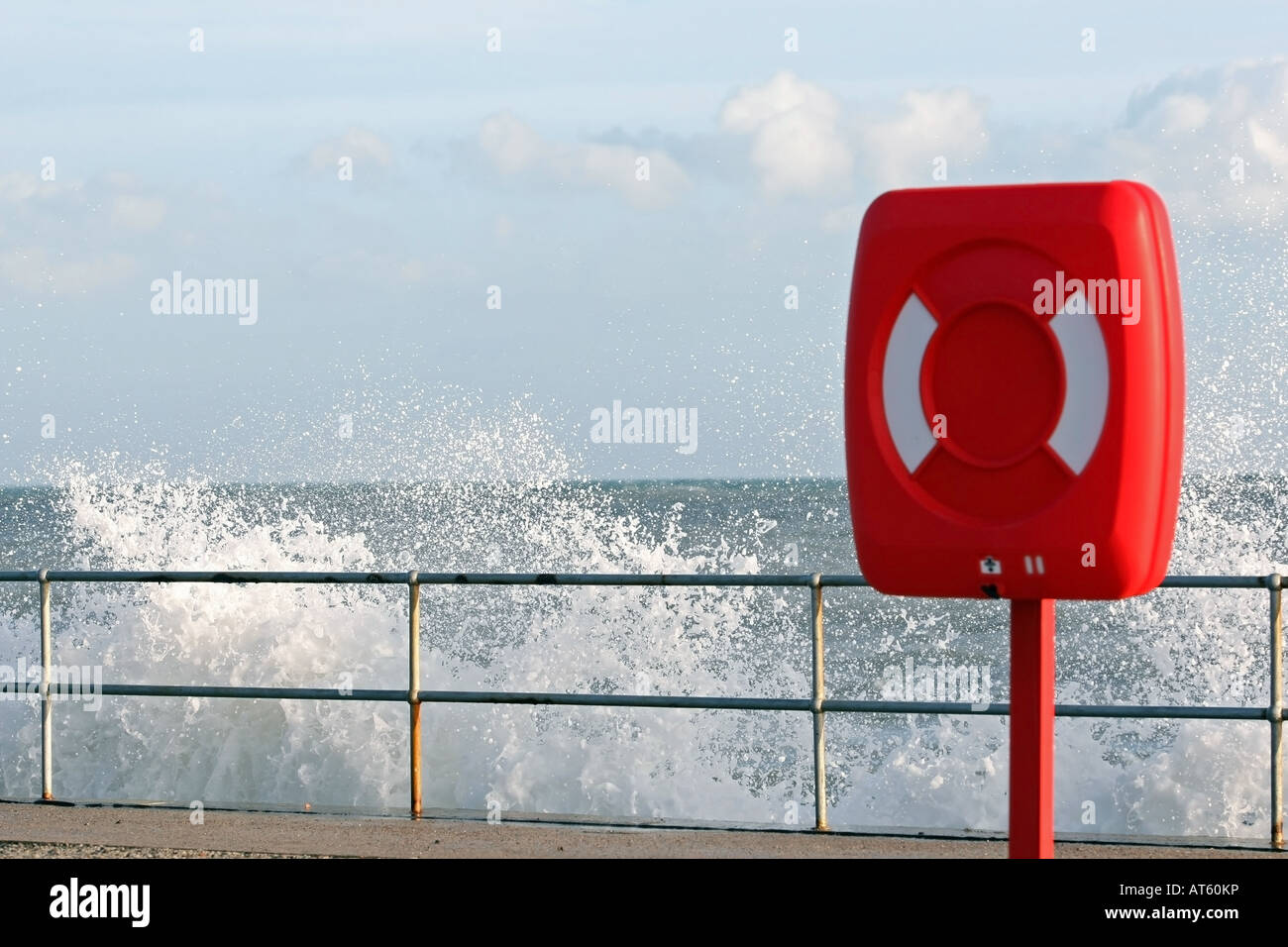A red life preserver in container on beach promenade with rough seas in ...