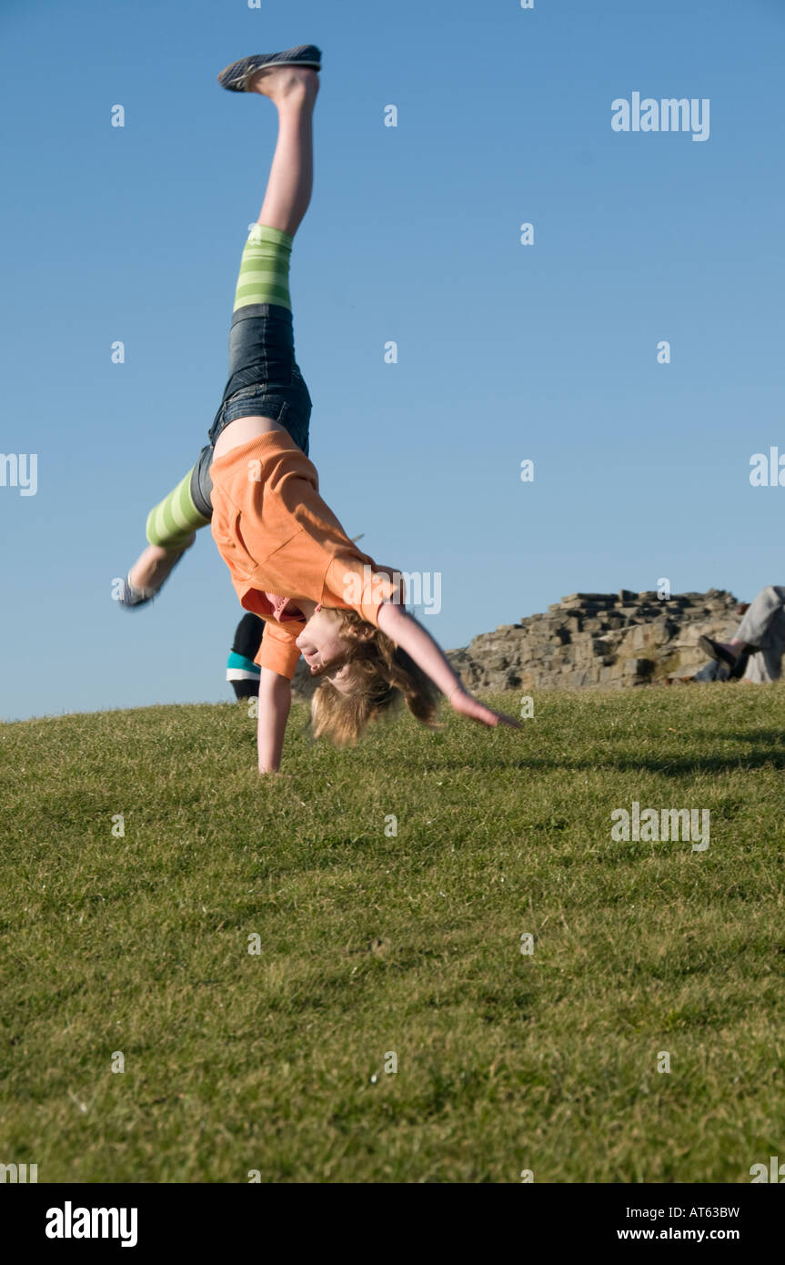 child playing outdoors doing cartwheel on the grass on a warm sunny day ...