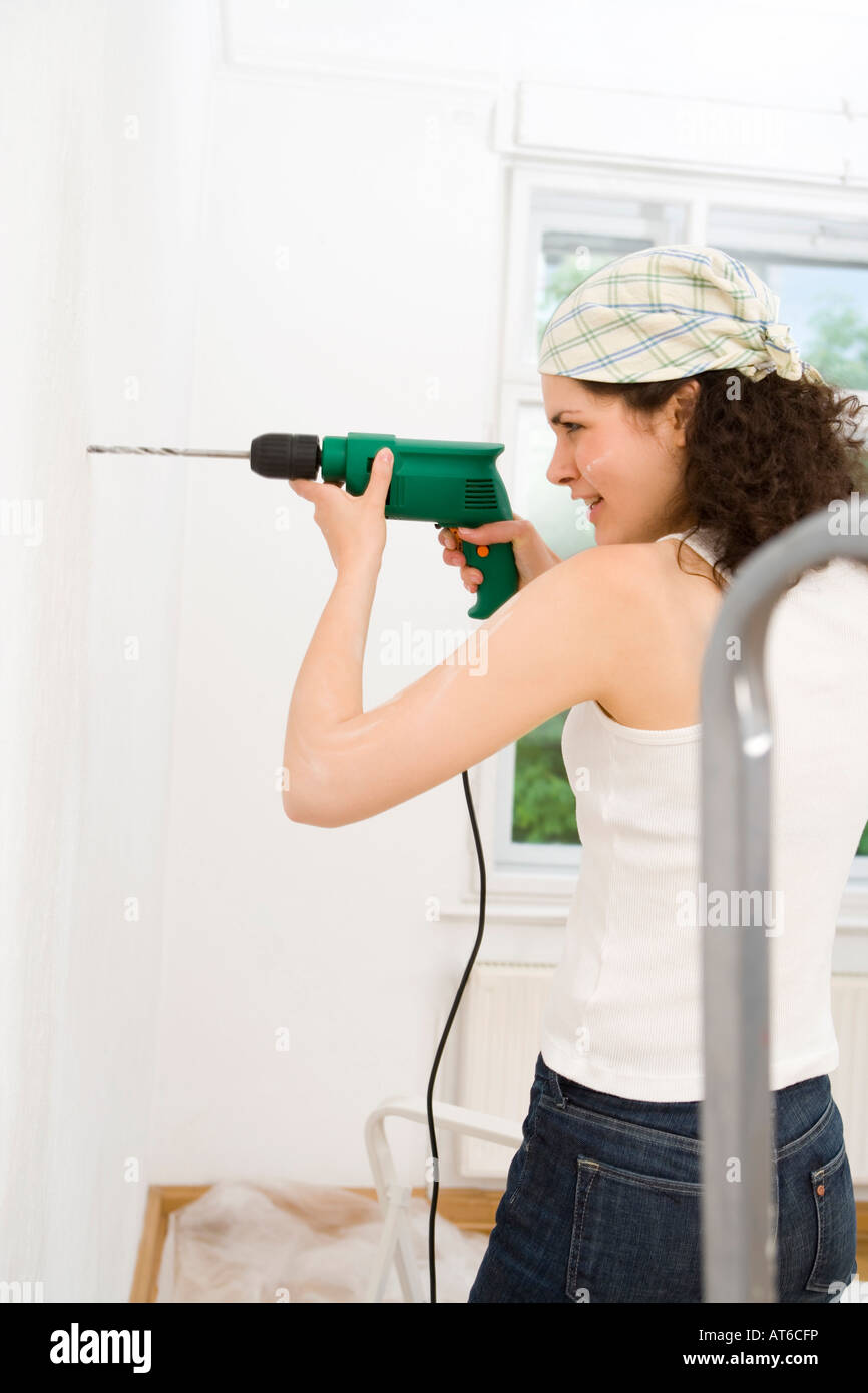 Young woman using drill Stock Photo - Alamy