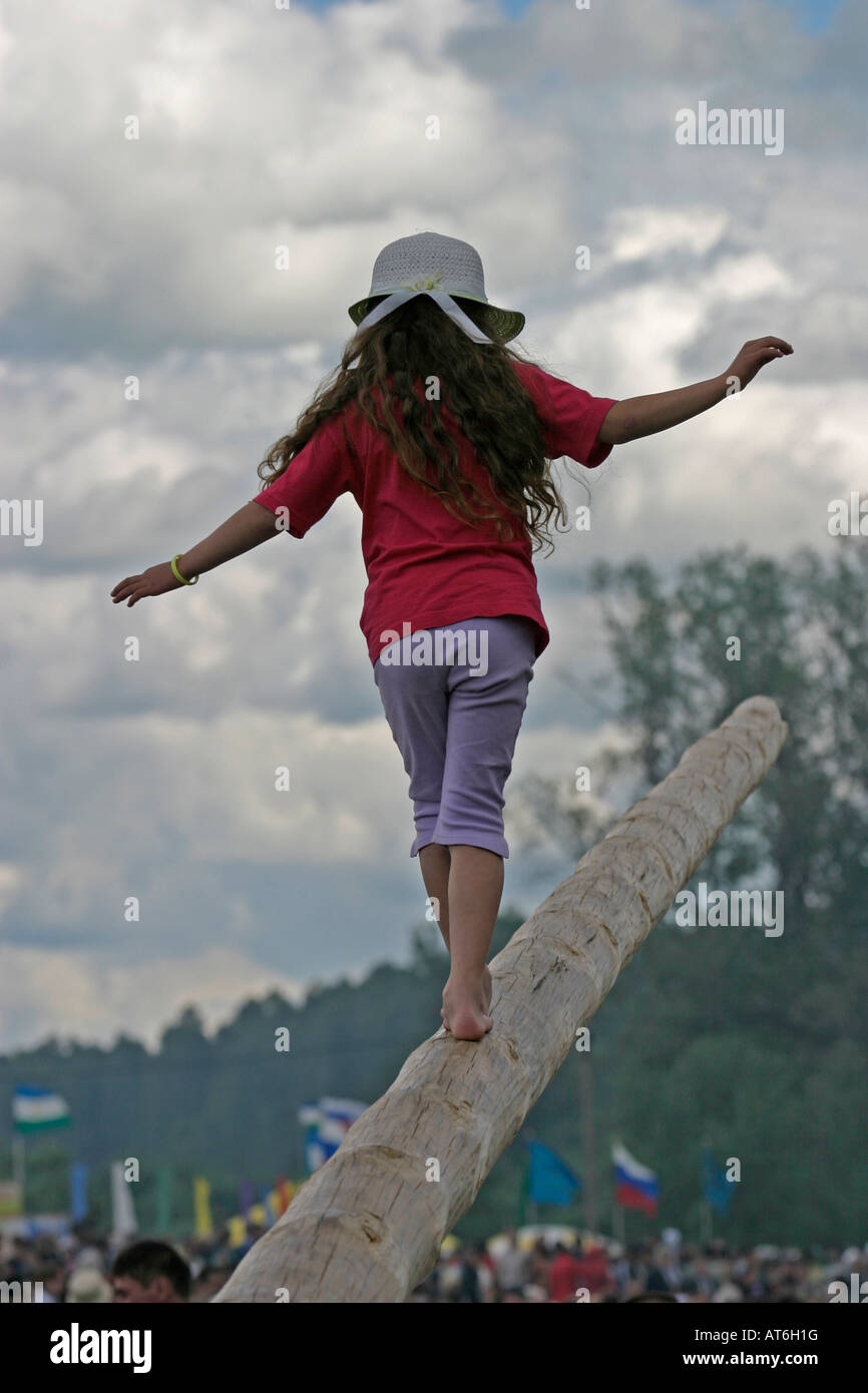Young girl walking to the end of a long bendy tree trunk balance ...