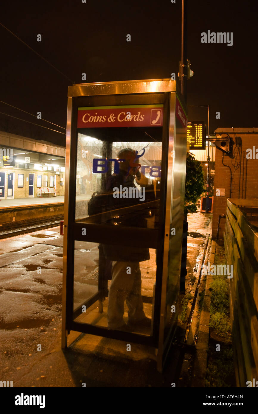 Man in Telephone Box Making Phone Call on Station Platform late at ...