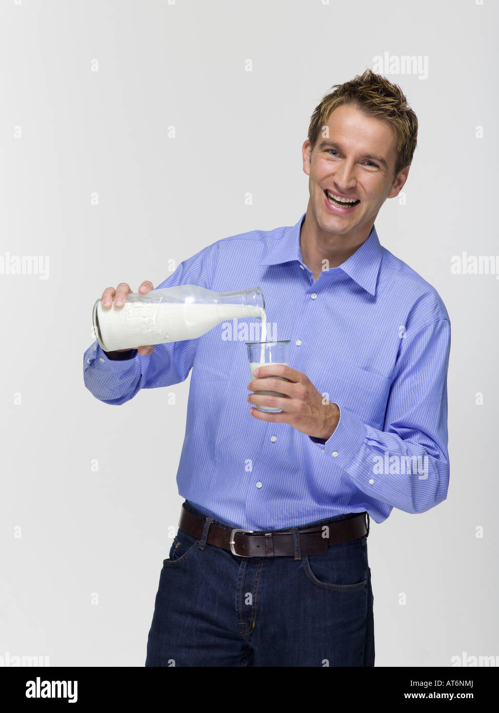 Young man pouring milk in a glass, portrait Stock Photo - Alamy