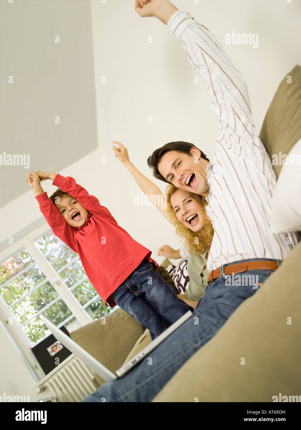 Young family in living room, cheering Stock Photo - Alamy