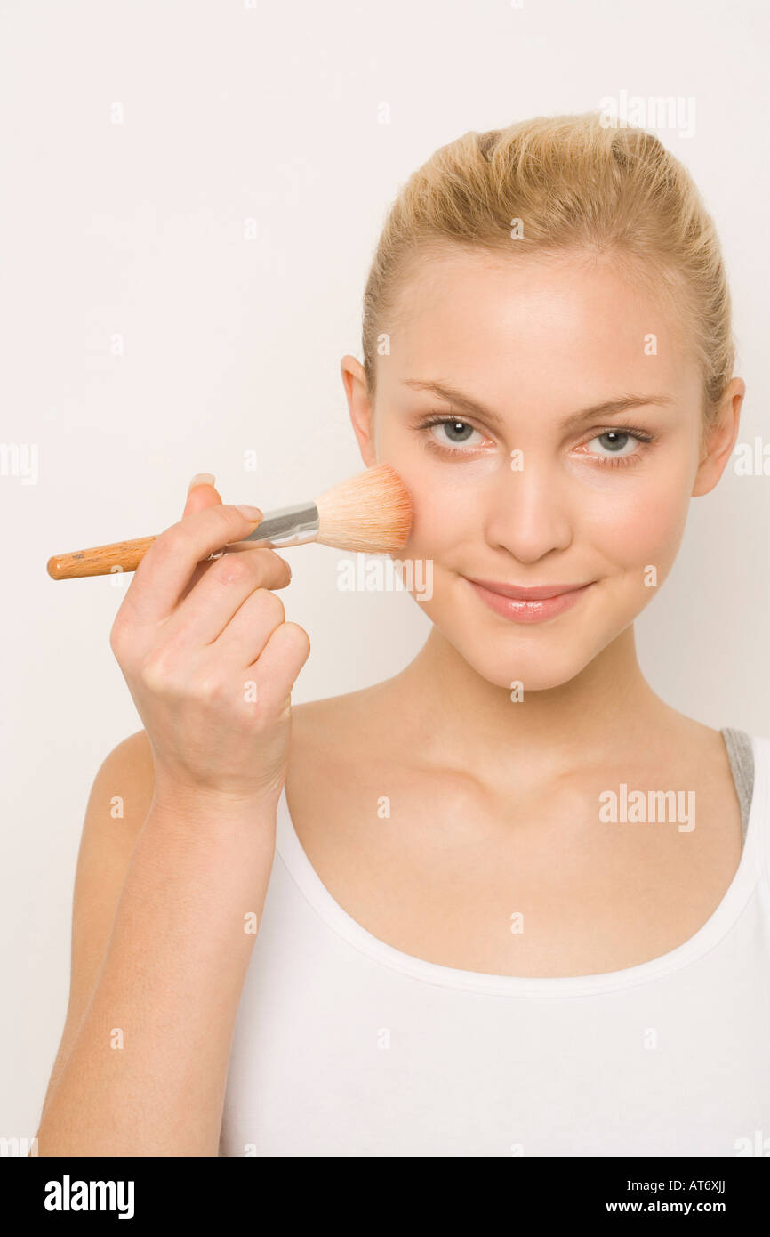 Young woman applying blush, smiling, portrait Stock Photo - Alamy