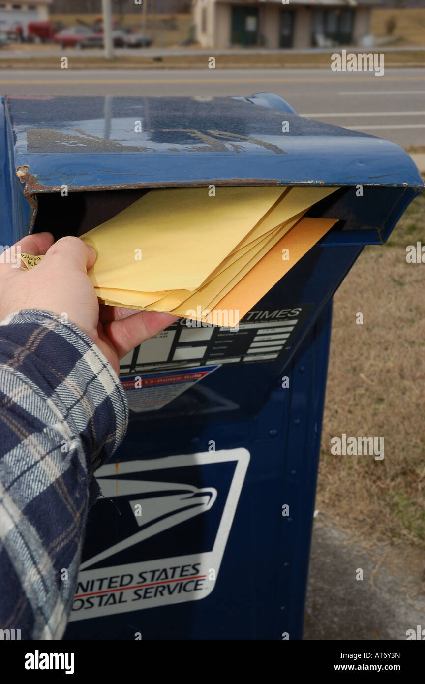A man puts mail in a drive by US Postal Mailbox on a winter day in ...