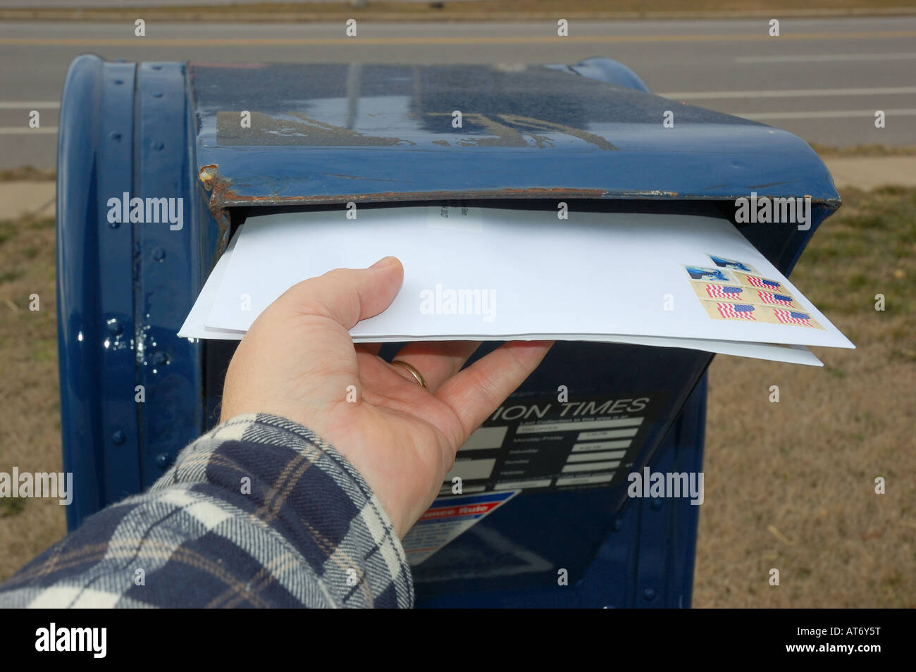 A man puts mail in a drive by US Postal Mailbox on a winter day in ...