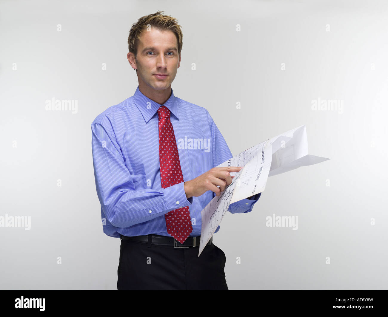 Young man holding construction plan, portrait Stock Photo - Alamy