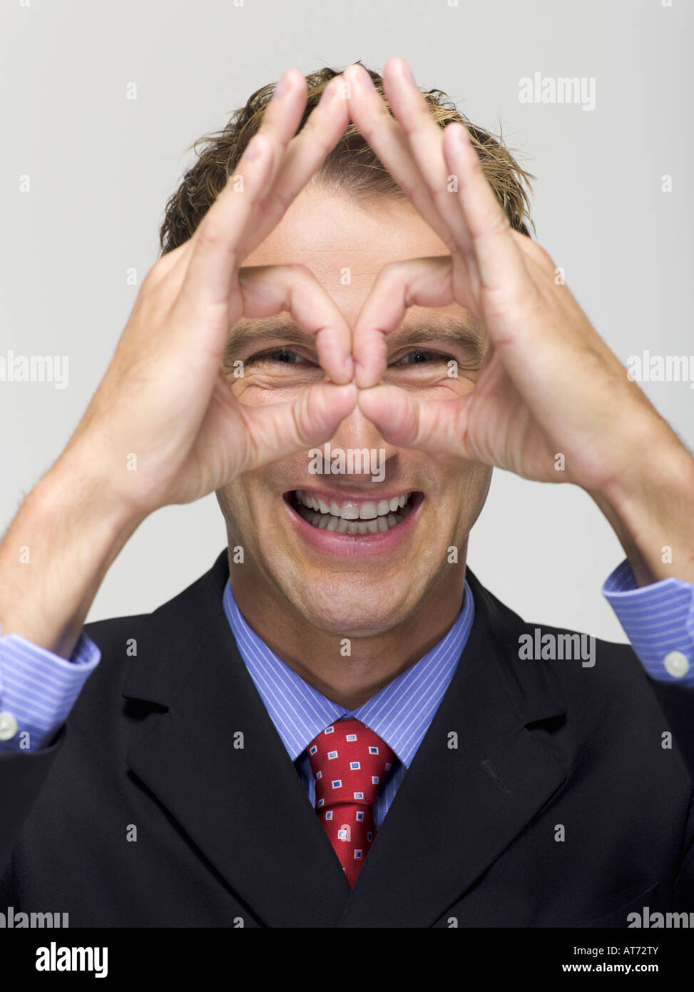 Young businessman making circles around eyes with fingers, portrait ...