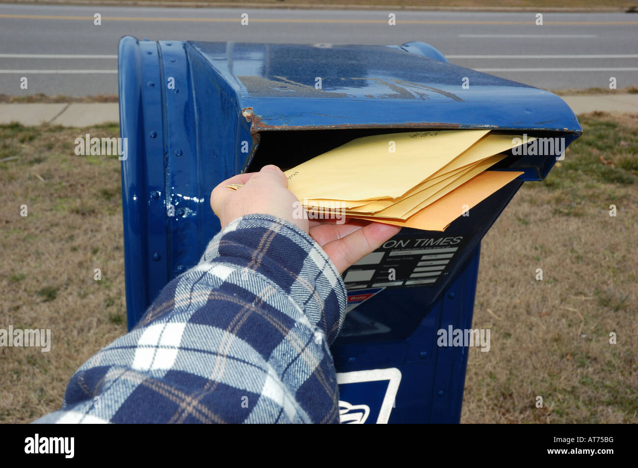 A man puts mail in a drive by US Postal Mailbox on a winter day in ...