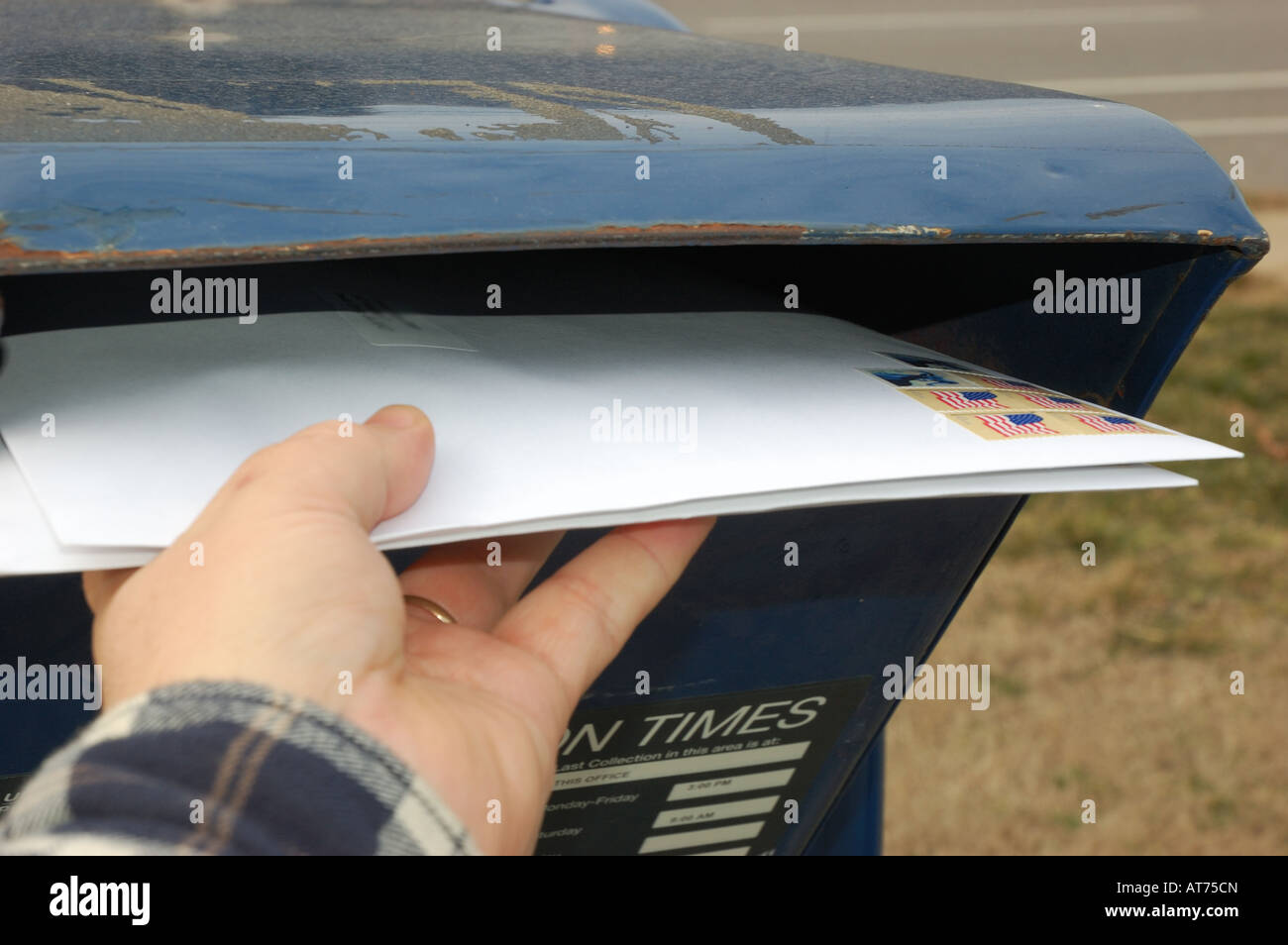 A man puts mail in a drive by US Postal Mailbox on a winter day in ...