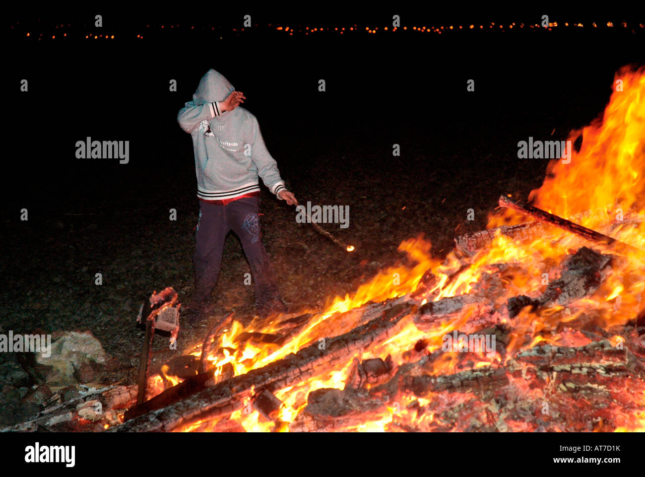 A youth shields his face from the intense heat of a bonfire as he ...