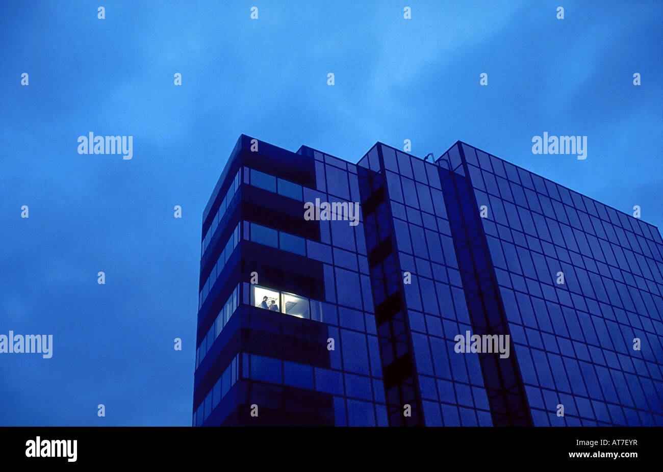 The facade of a building at night with a single corner office light on ...
