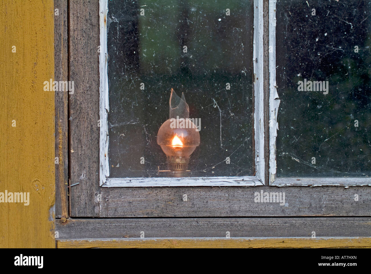 old oil lamp with broken glass burning at window of a timber wooden ...