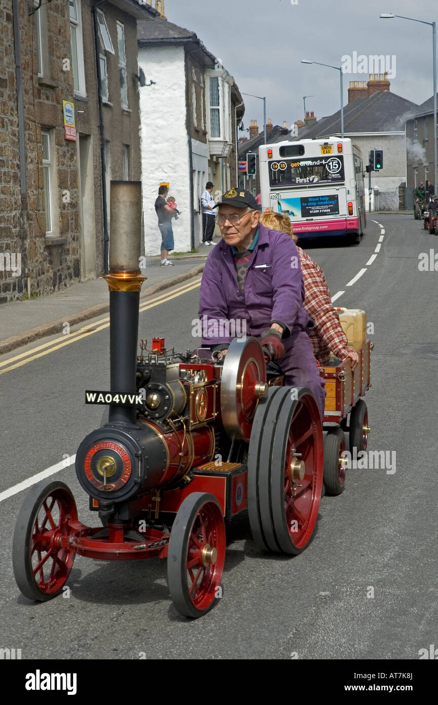 a man driving a scale model steam traction engine through the streets ...