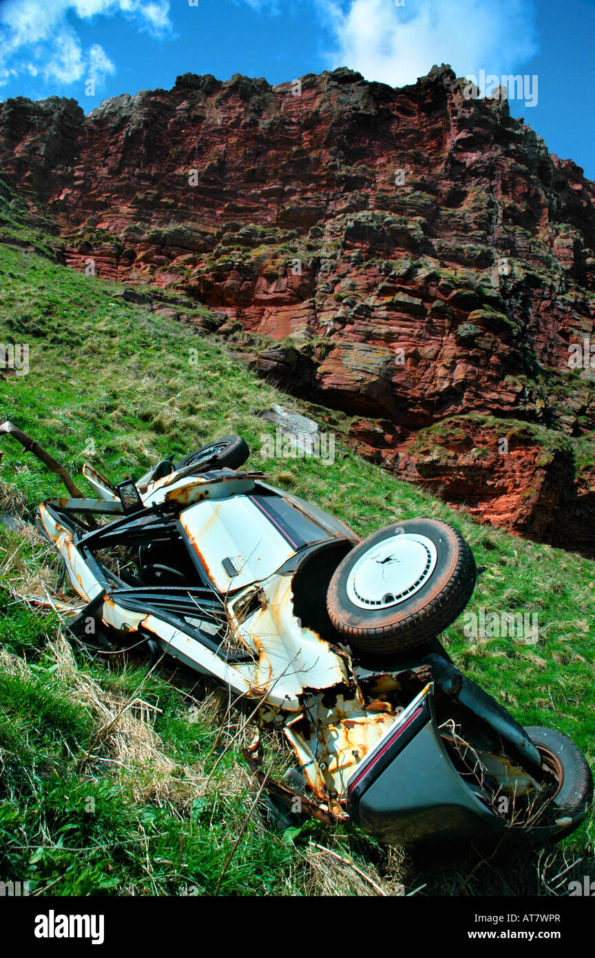 a fallen car lies on its back rusting with towering cliffs in the ...
