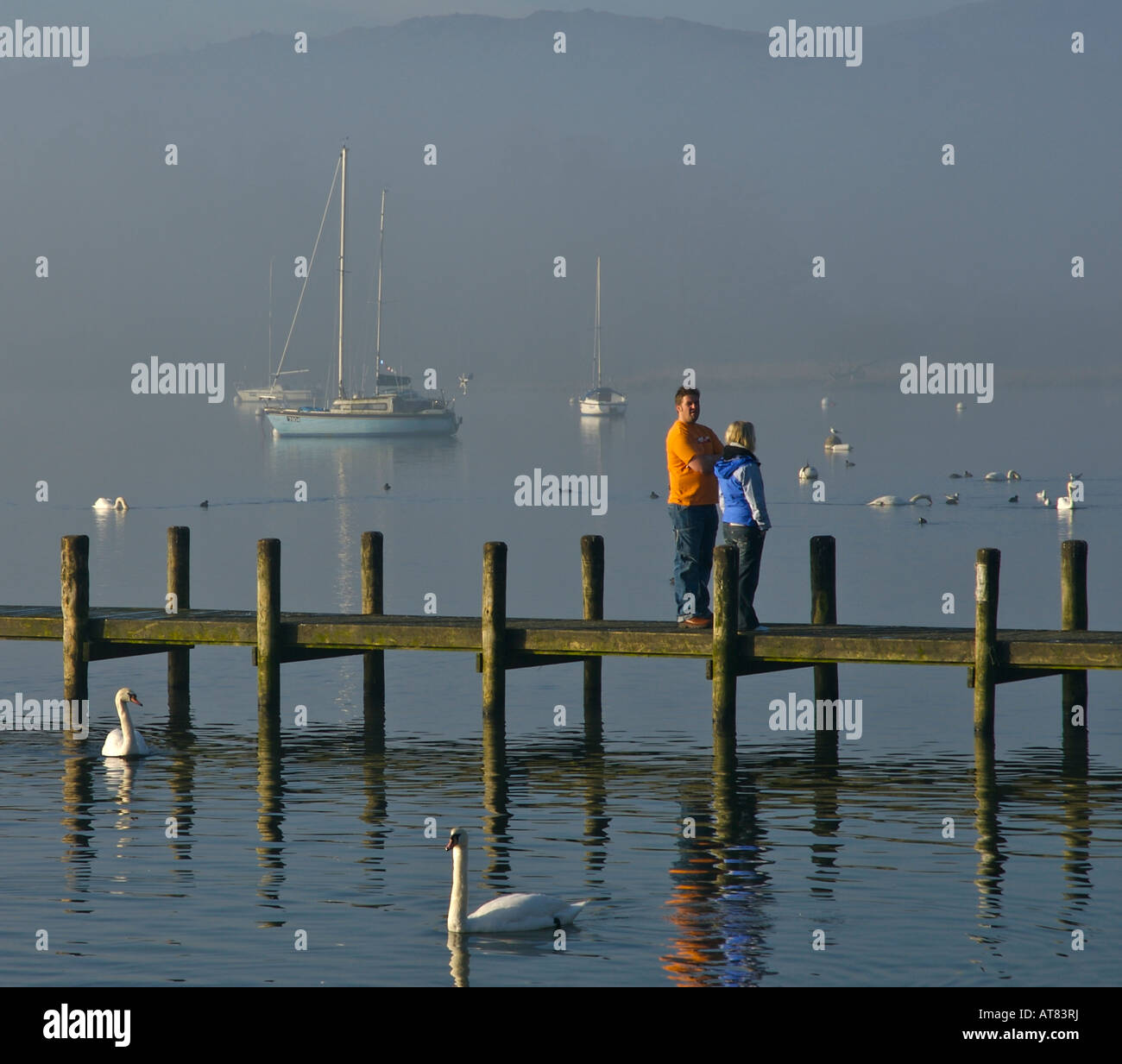 Two people on pier at Waterhead, Lake Windermere, Lake District ...