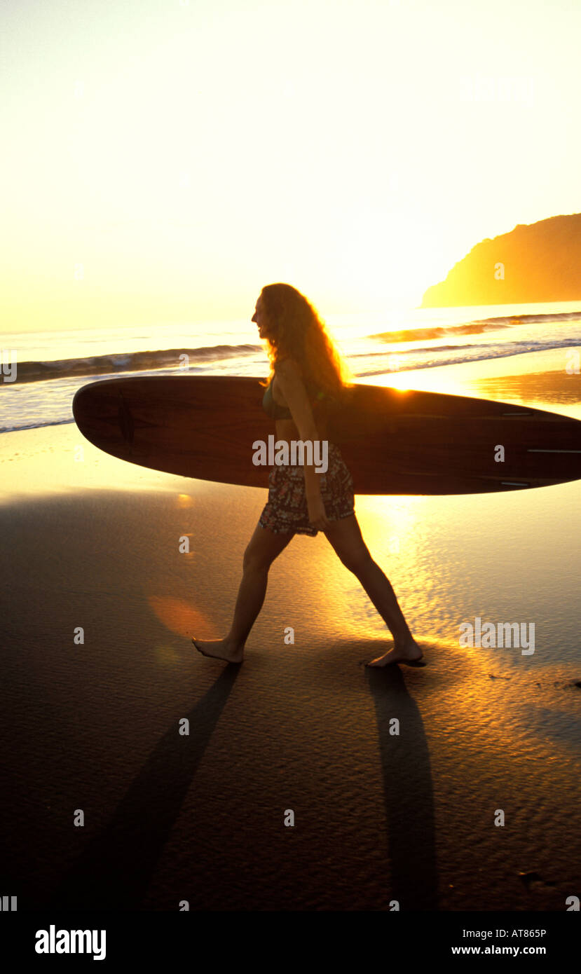 Woman going out surfing at sunset in Waipio Valley Stock Photo - Alamy