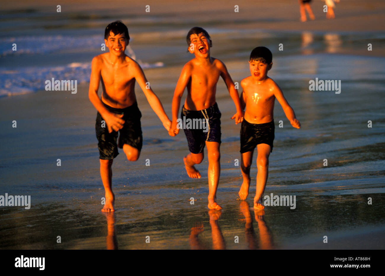 Three boys running on the beach on the Big Island Stock Photo - Alamy