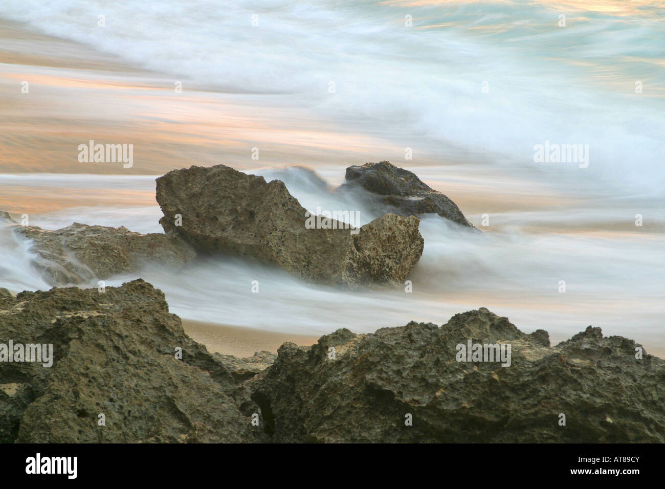 wind and waves sweep over the beach's sand and rocks under beautiful ...
