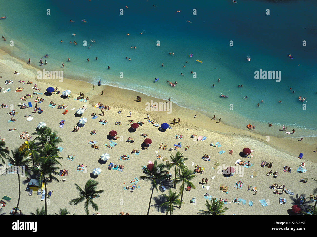 Visitors line the beach at Waikiki while on vacation , island of Oahu ...