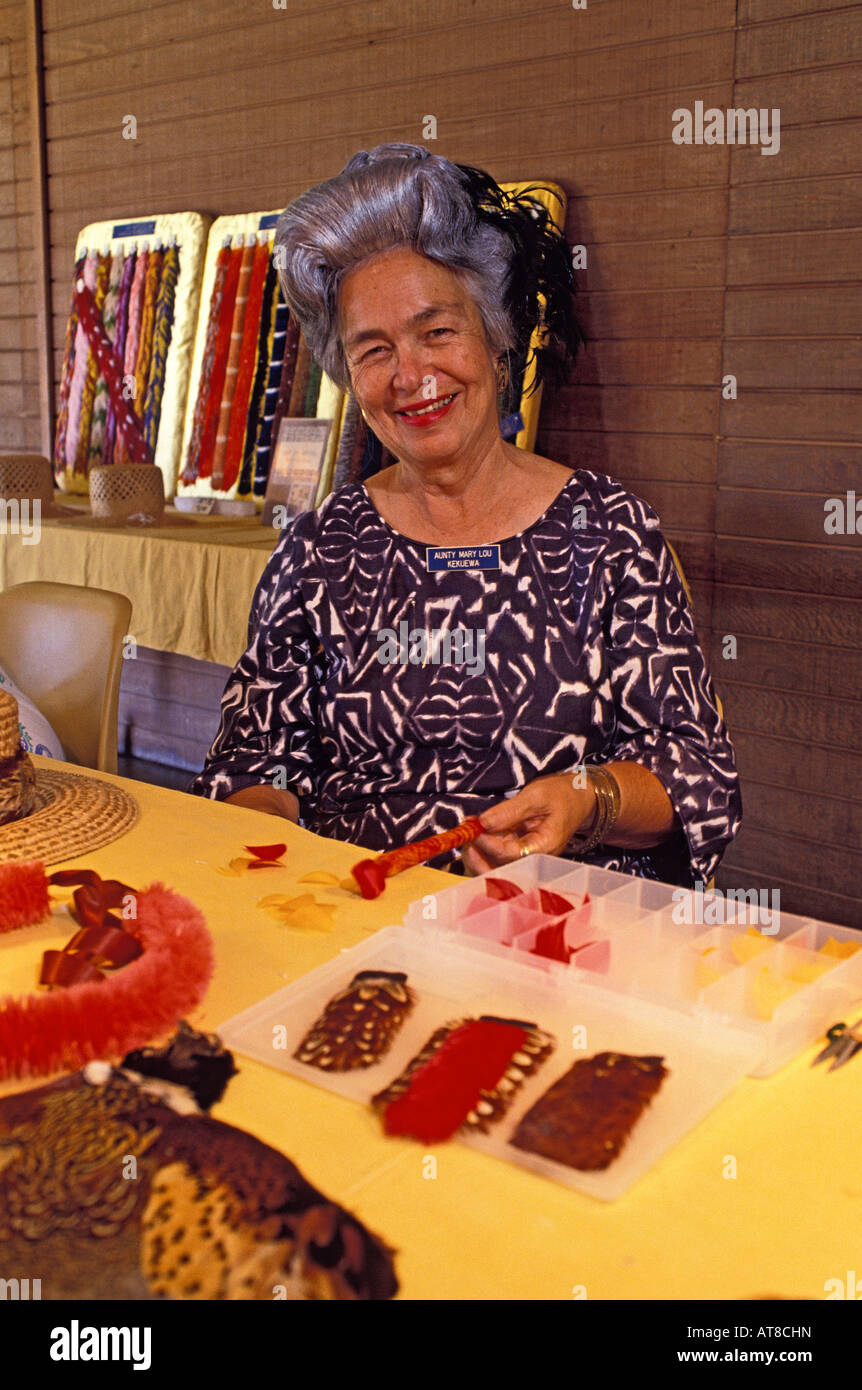 A female kapuna (elder) smiles as she sits at a table with feather lei ...