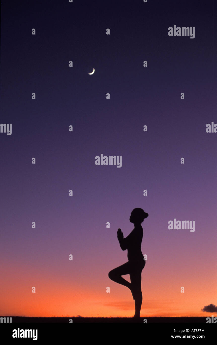 Female yoga practitioner silhouetted against purple & orange sky at ...