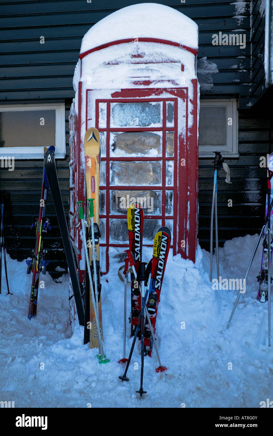Red Telephone box surrounded by snow and skis, Cairngorms National Park ...