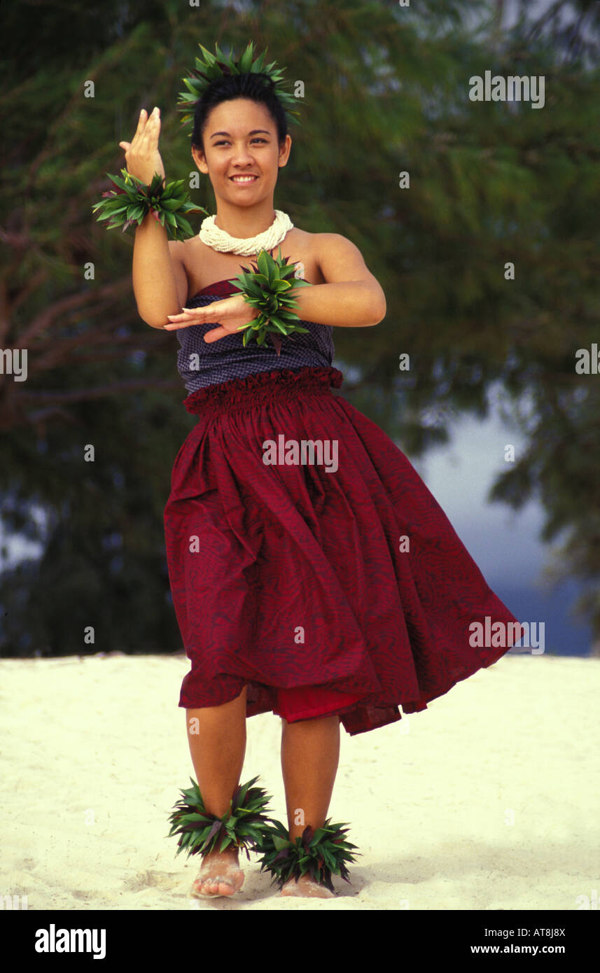 Young woman dancing hula on the beach wearing kupee on wrists and ...