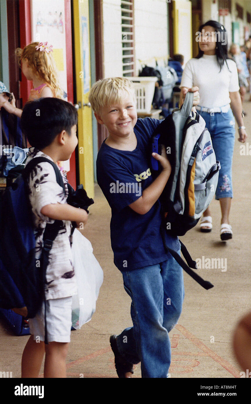 Elementary school hallway with children putting on backpacks after ...