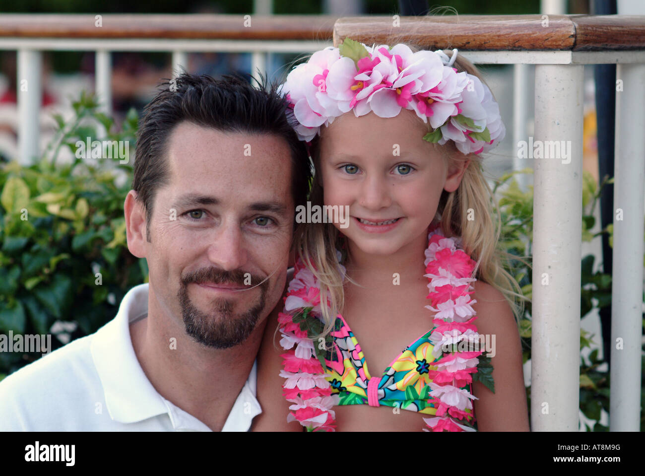 Portrait of a father with his daughter wearing flower leis and hula ...