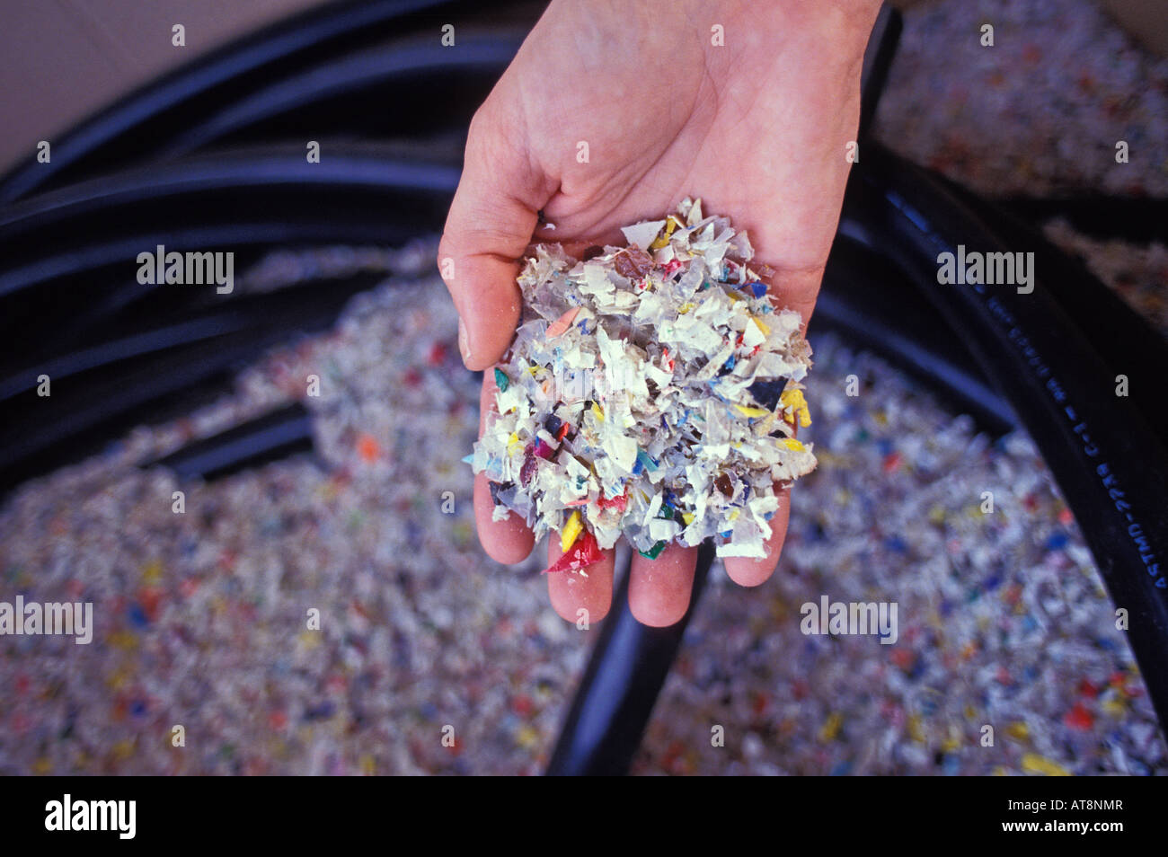 A hand scoops out some shredded plastic from a recycling bin Stock ...