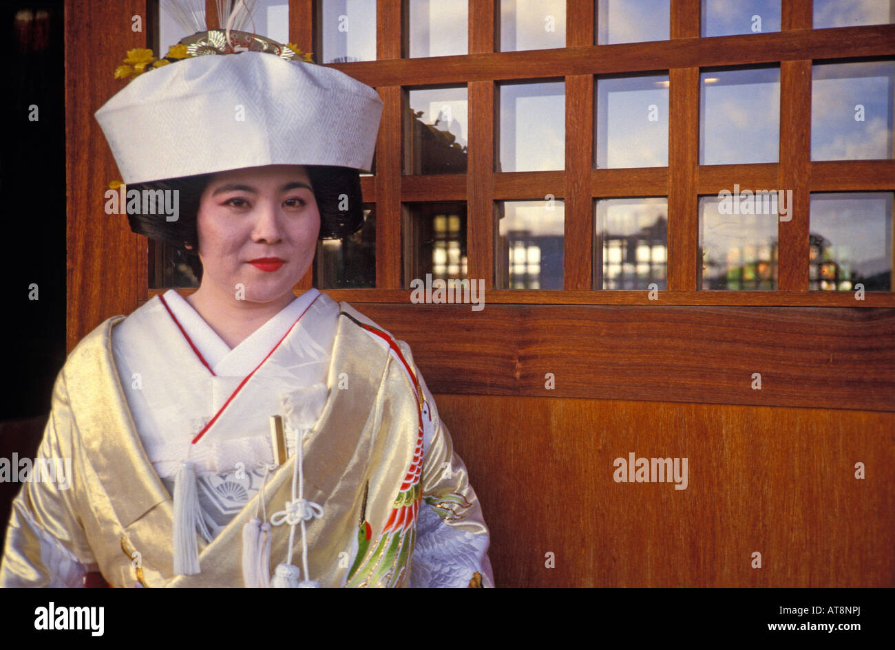 A young Japanese bride in traditional attire stands outside a temple in ...
