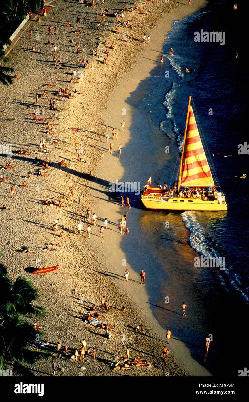 A large yellow catamaran loaded with tourists sets sail in the late ...