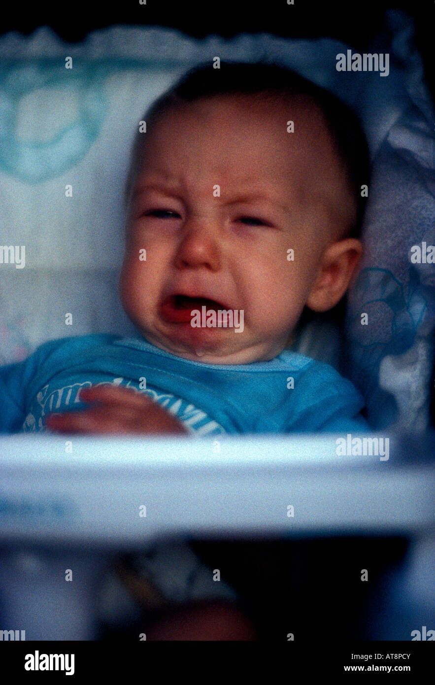 A six month old baby boy cries while sitting in his highchair Stock ...