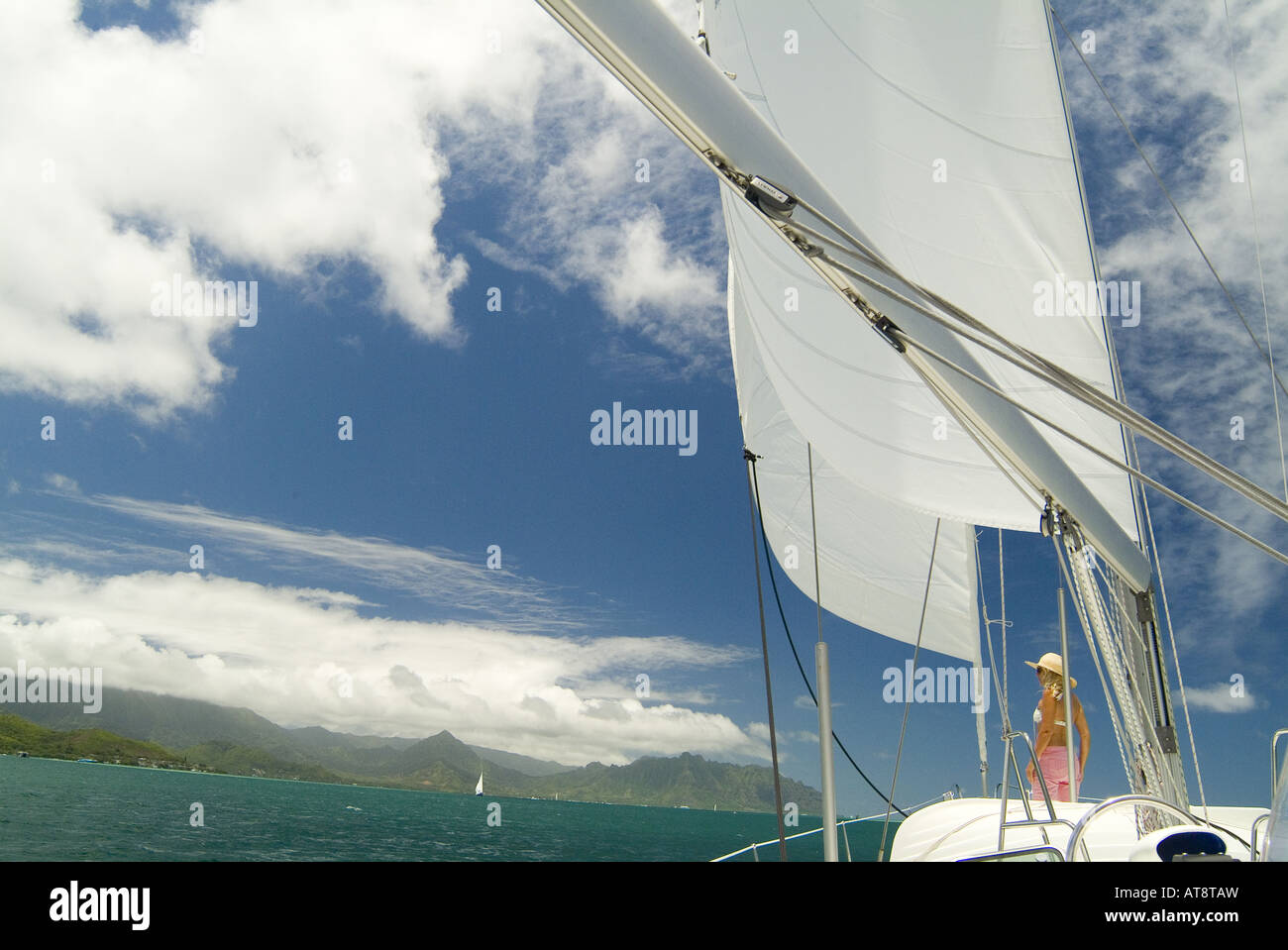 A woman enjoys a peaceful sail and the beautiful scenery on Kaneohe Bay ...