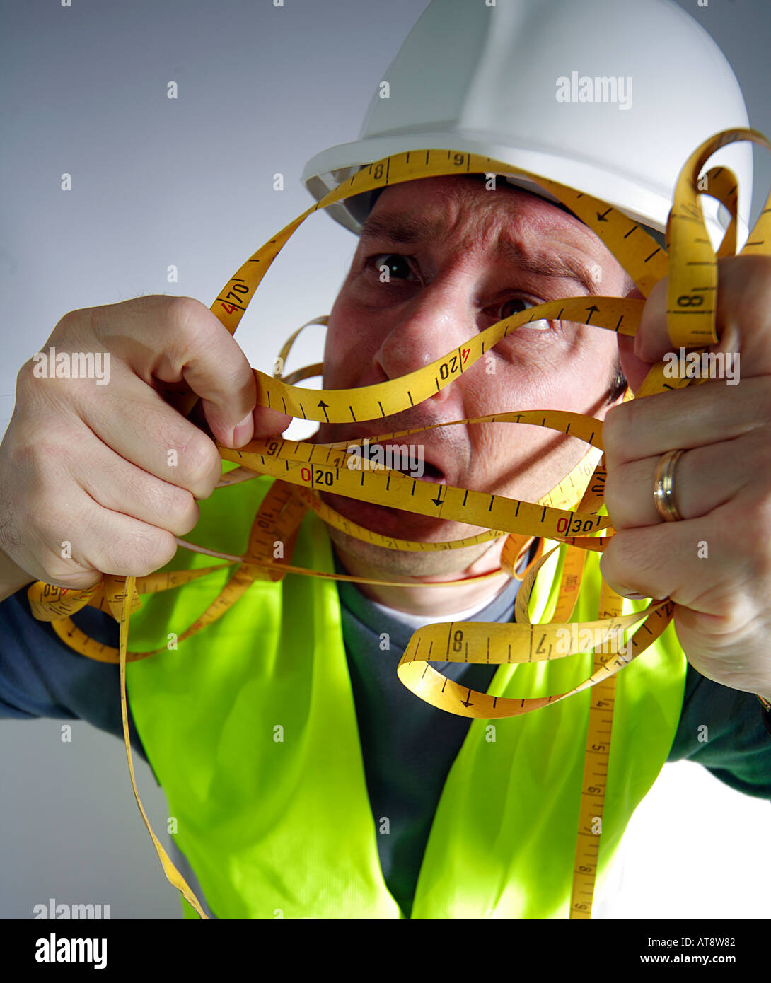 Construction worker with a tangled measuring tape Stock Photo - Alamy