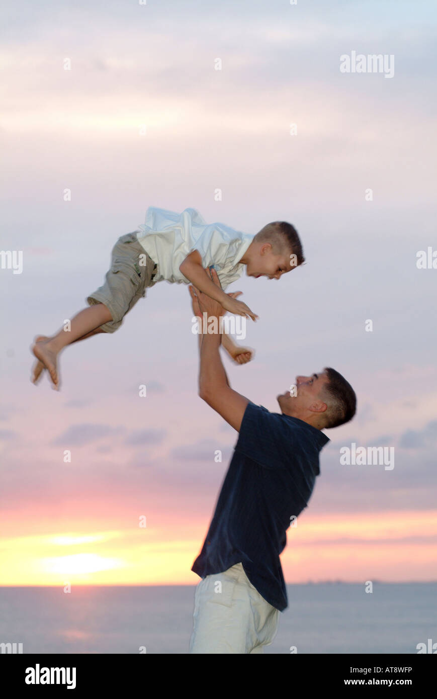 Father throwing son up in the air near the ocean at magic island park ...