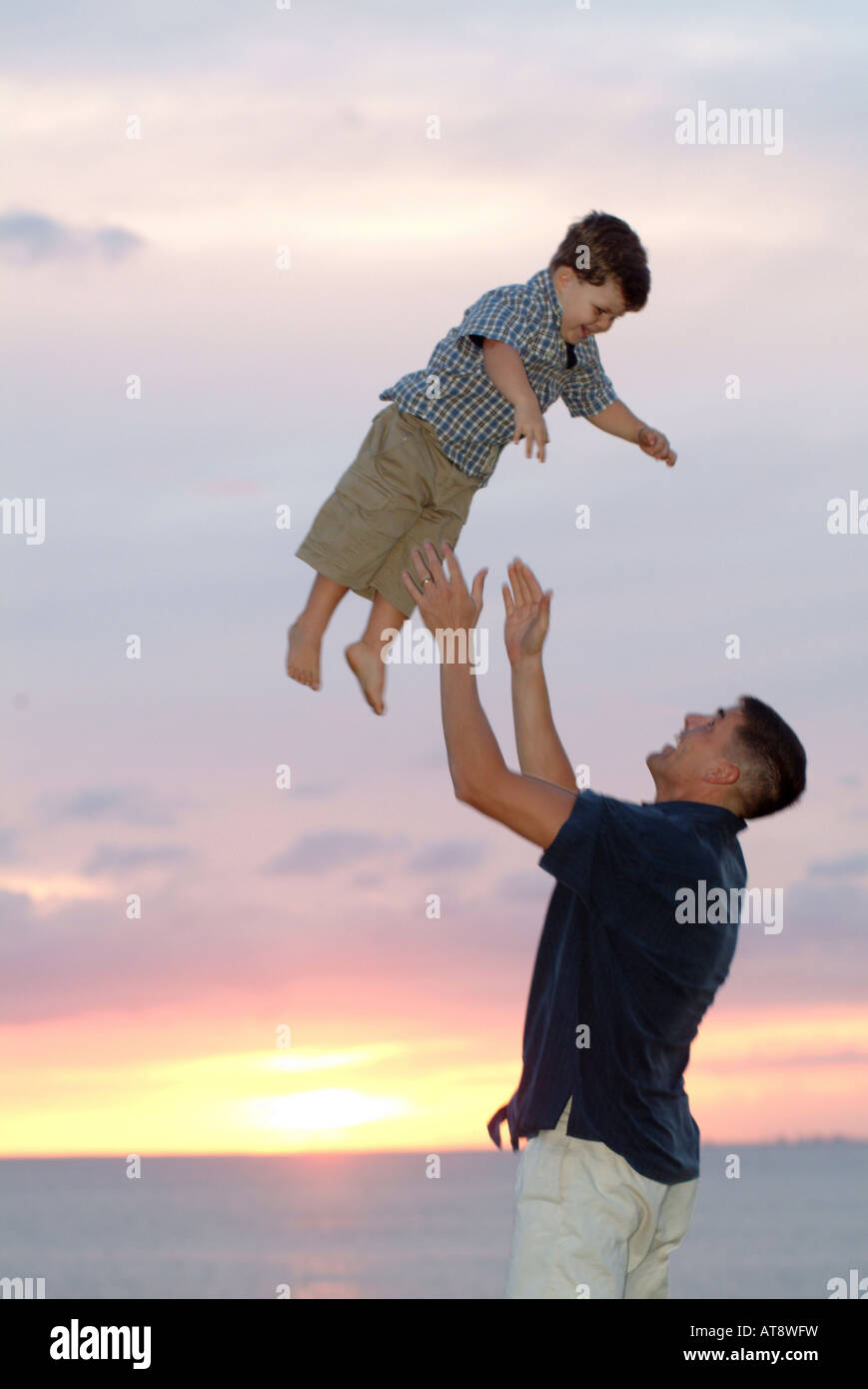 Father throwing son up in the air near the ocean at magic island park ...