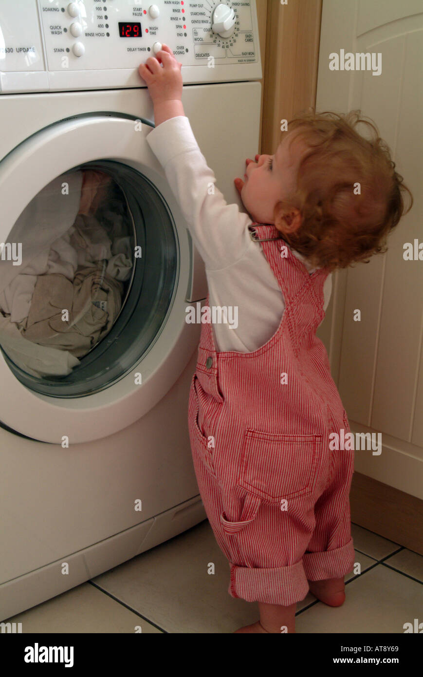 Toddler playing with the buttons on a washing machine Stock Photo - Alamy