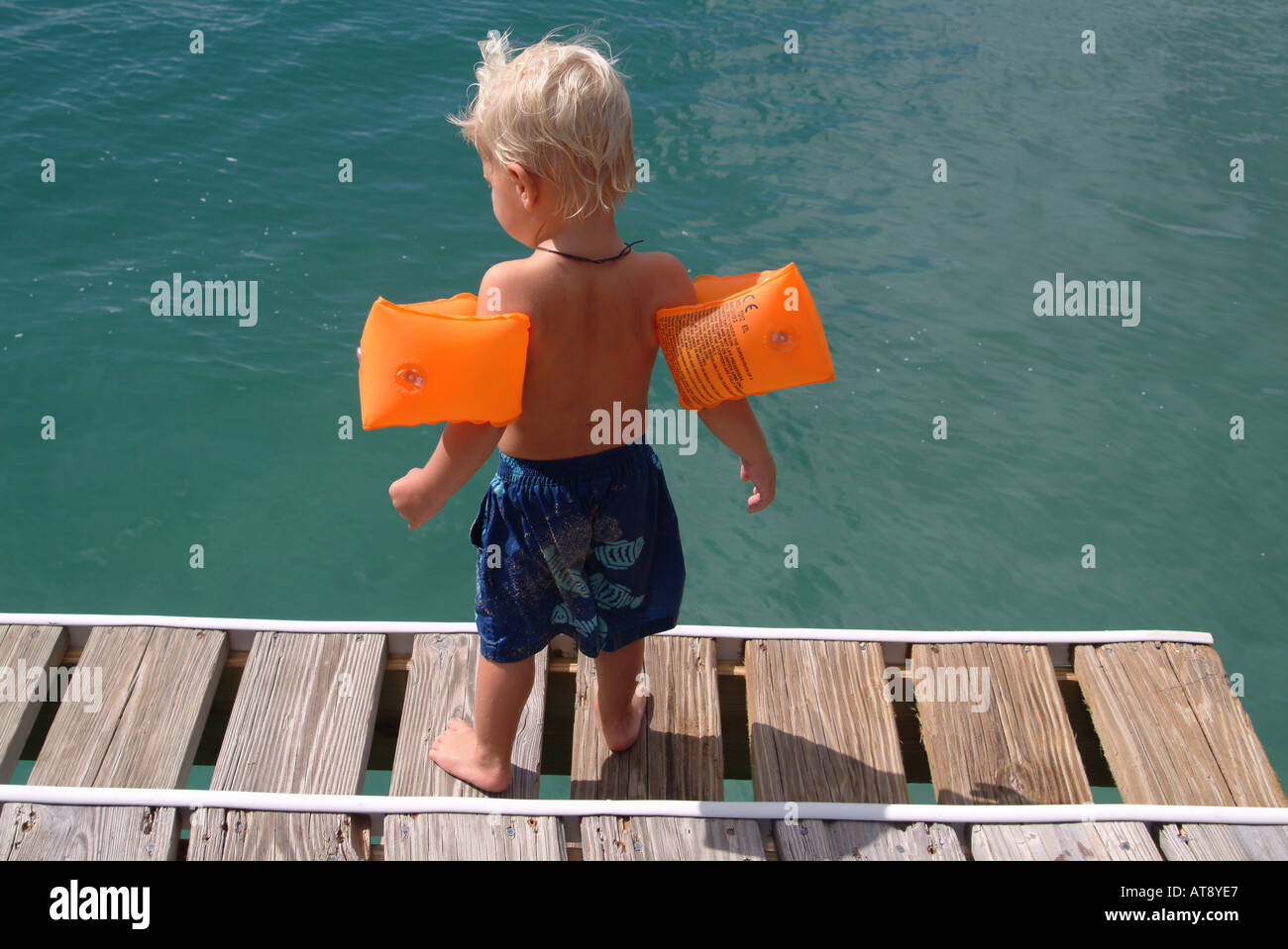 Little boy standing on a wooden pier and wearing armbands Stock Photo ...