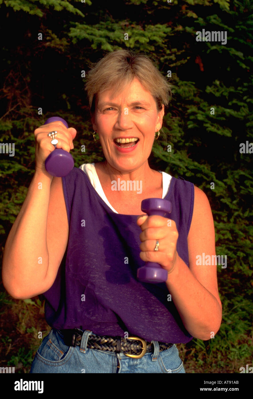 Happy woman age 56 doing an upper body workout with color coordinated ...